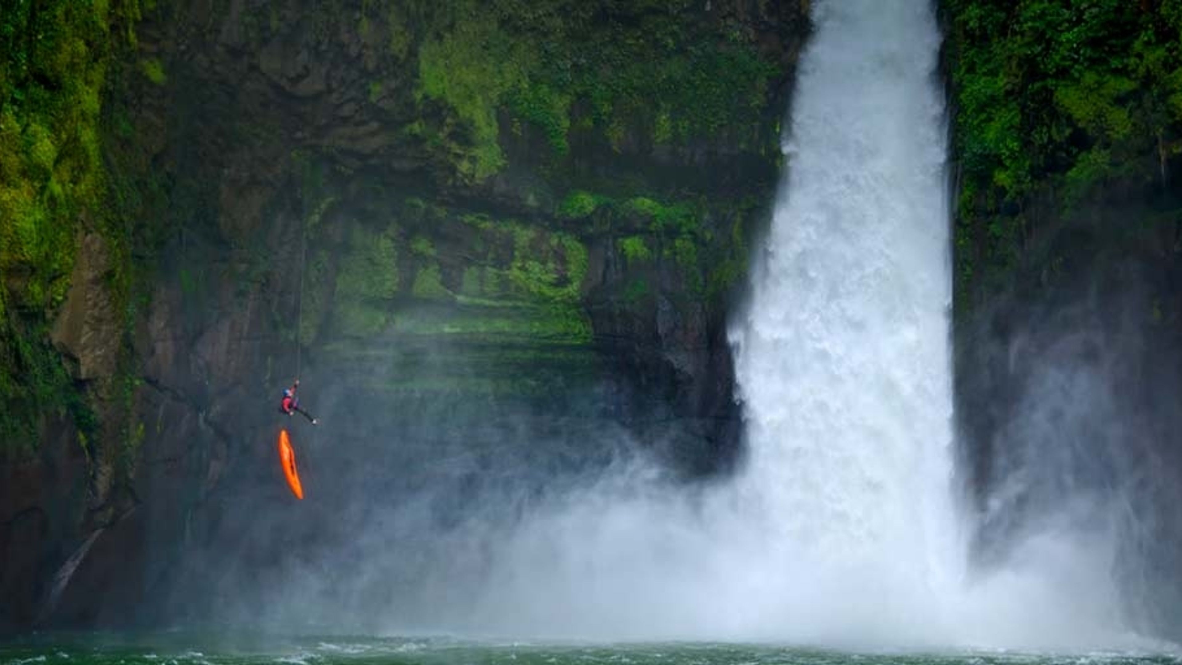 A man rappels down a huge cliff next to a waterfall on the Rio Alseseca ...