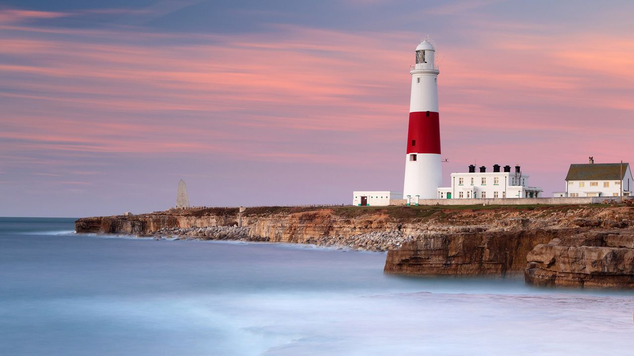 Dawn sunlight and waves at Portland Bill lighthouse, Dorset, England ...